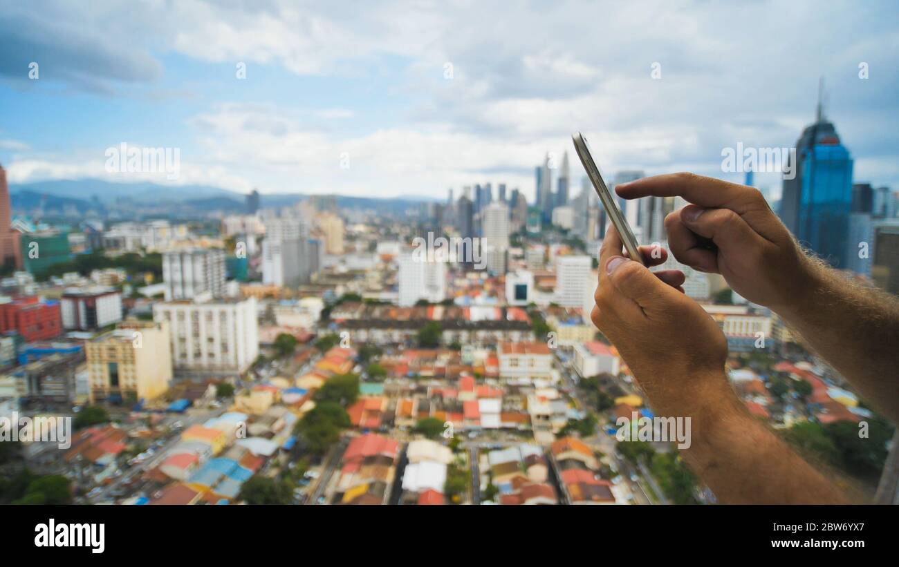 The guy is working with a smartphone on a blurred background. Kuala ...
