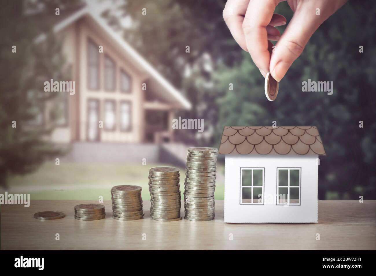 House model with coins Stack on table success on blur background with ...