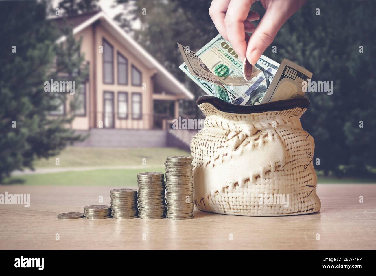 Hand put coin in Bag with US dollar bills, coins Stack on table, blur ...