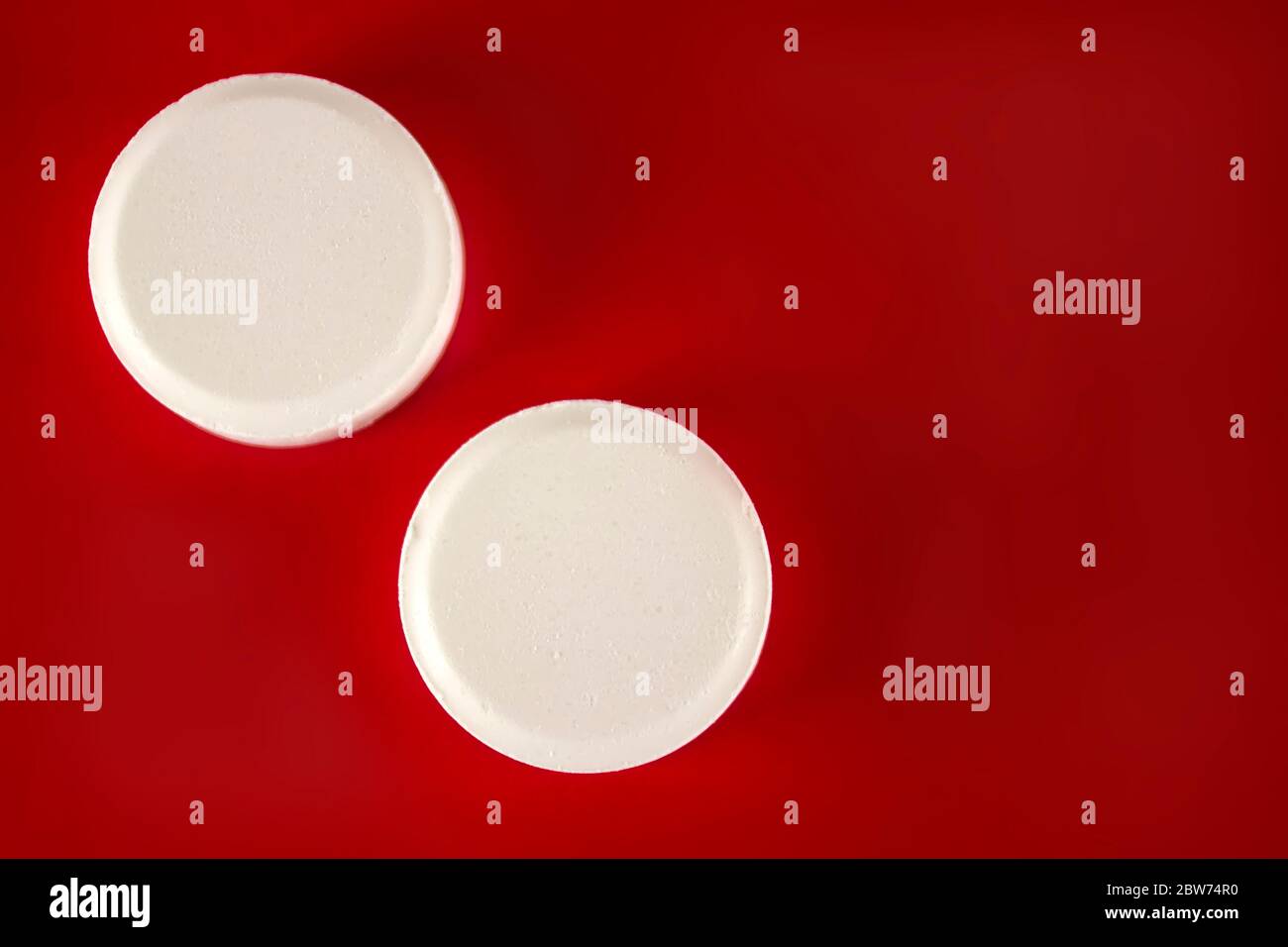 White medication pills lie on a red background. Medicine, pharmacy and ...