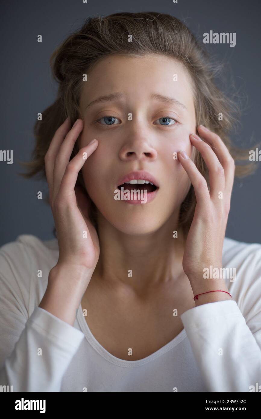 Portrait of young startled lady sadly looking in camera while holding ...