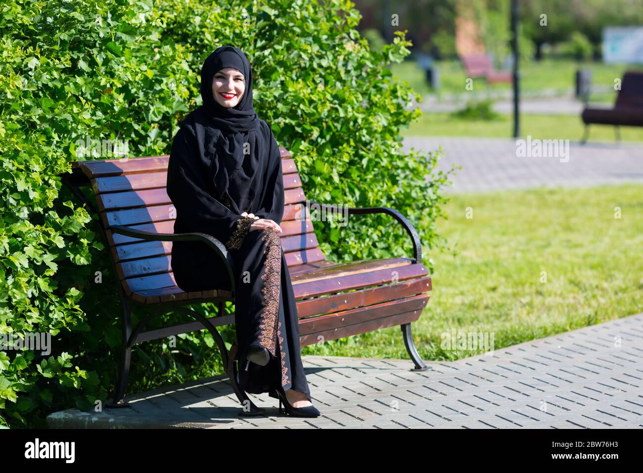 Islamic girl smiles broadly, resting on a park bench Stock Photo - Alamy