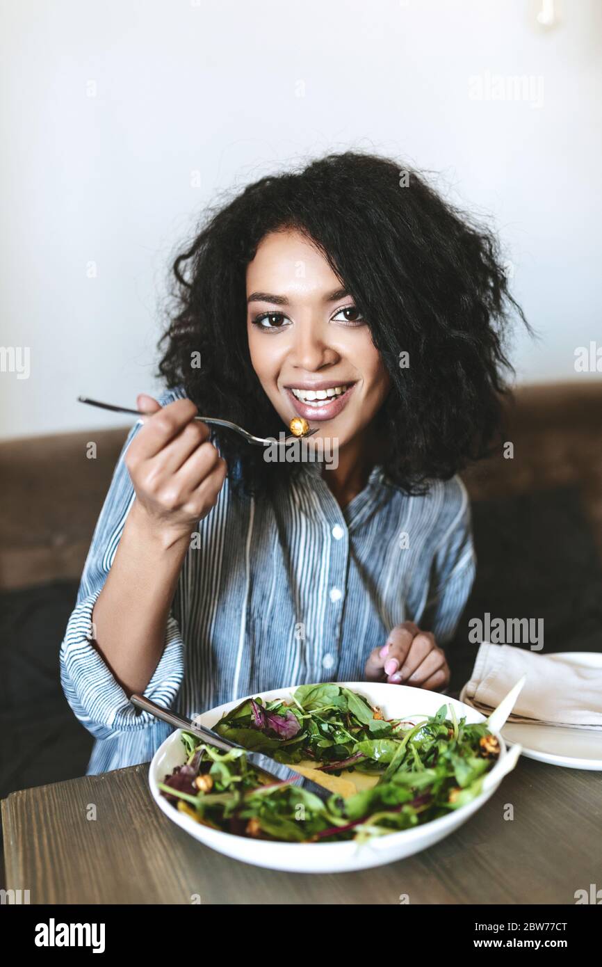 Pretty African American girl eating salad in restaurant. Portrait of ...