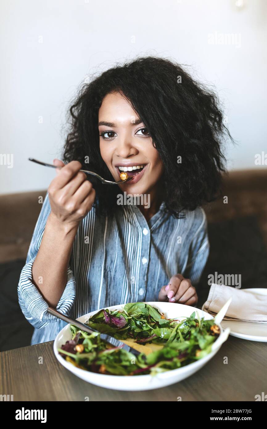 Nice African American girl eating salad in restaurant. Portrait of ...