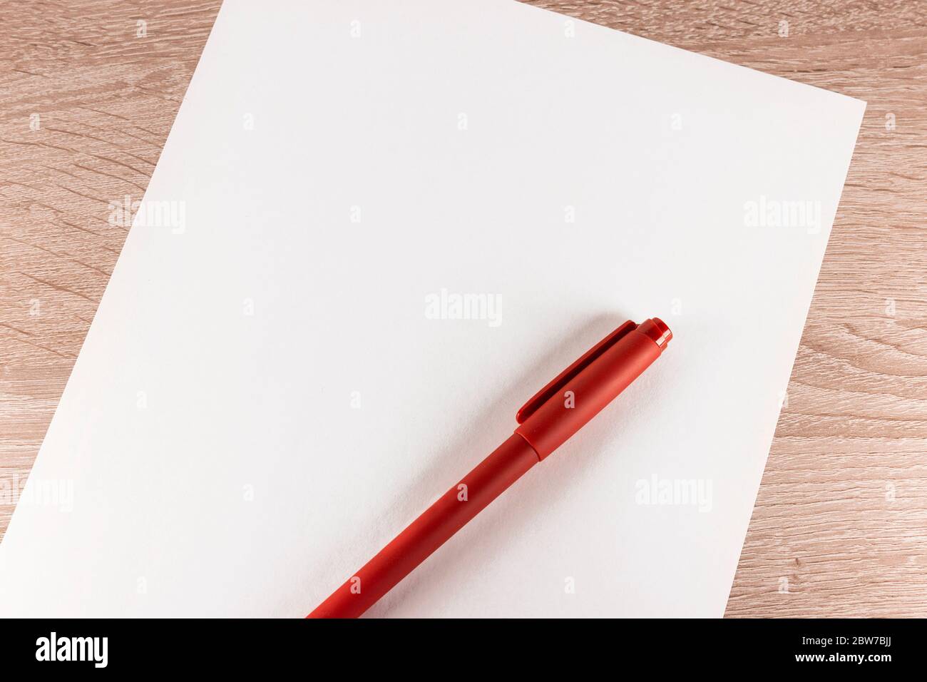 Blank sheet of paper and pen on bright wooden office desk. Ballpoint ...