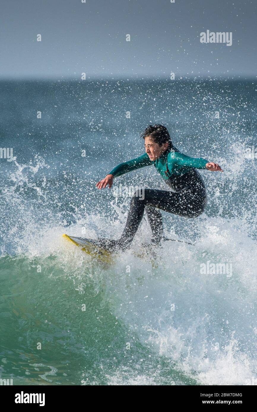 A young teenager surfing the crest of a wave in wild surfing conditions ...