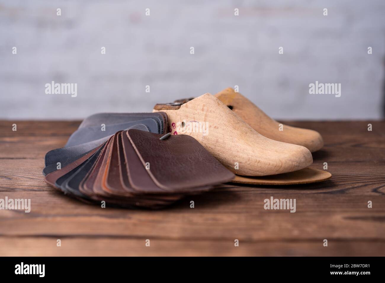 Leather samples for shoes and wooden shoe last on dark wooden table ...