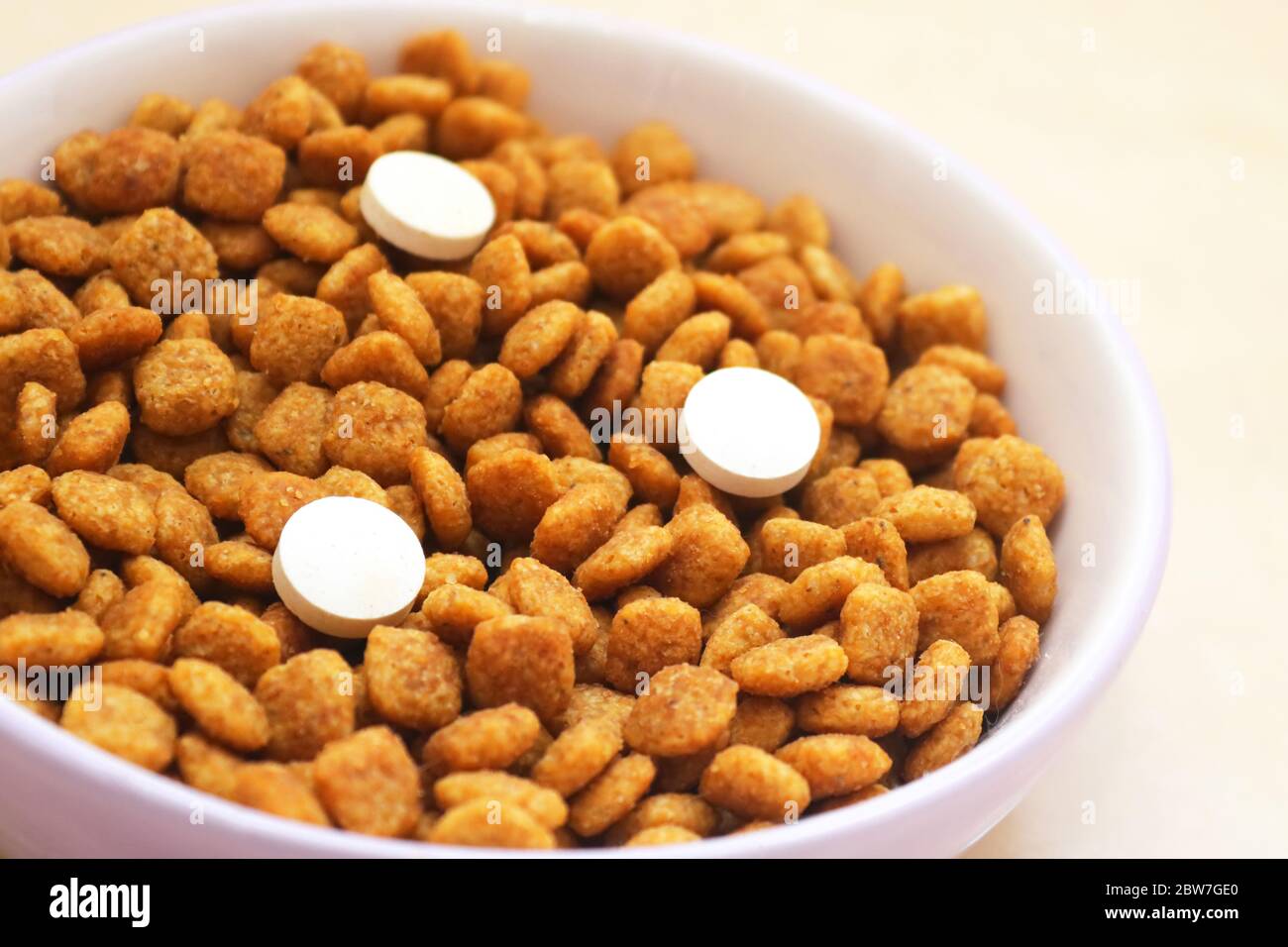 Cat food with three pills in a bowl on the floor. Vitamins for cats ...