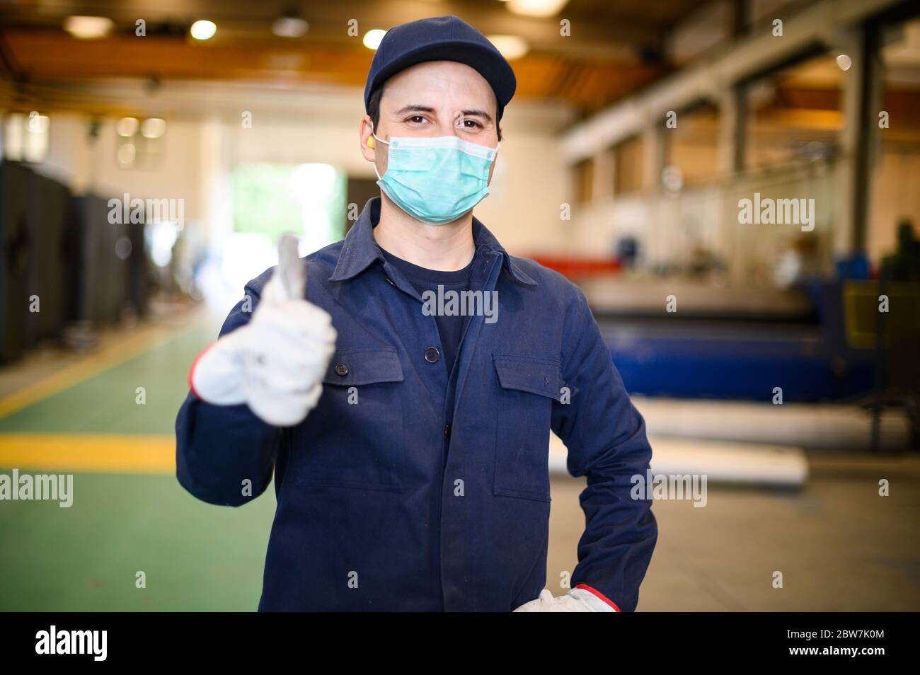 Portrait of a worker in an industrial plant wearing a mask and giving ...