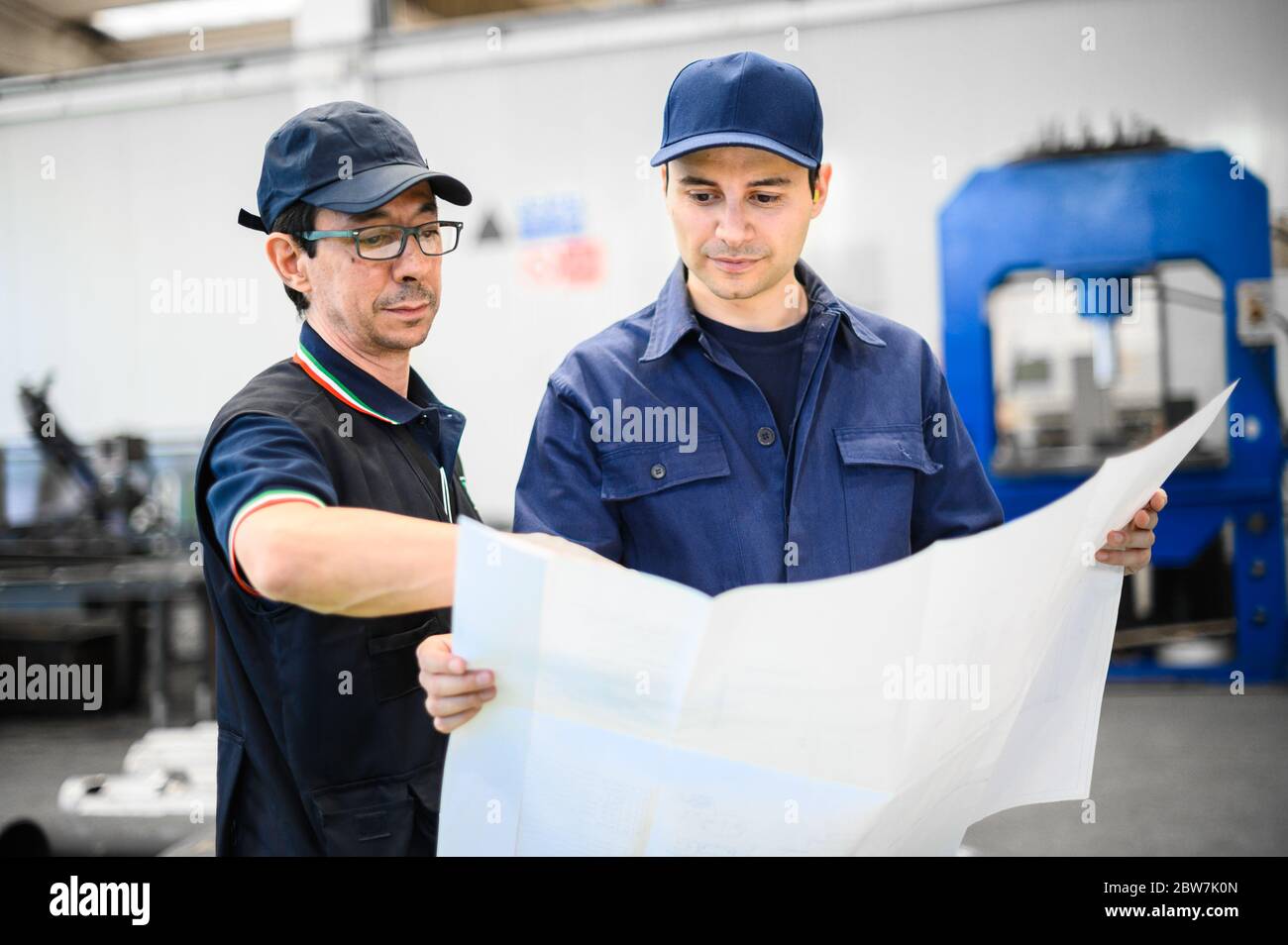 Two engineers looking at a blueprint in a facility Stock Photo - Alamy