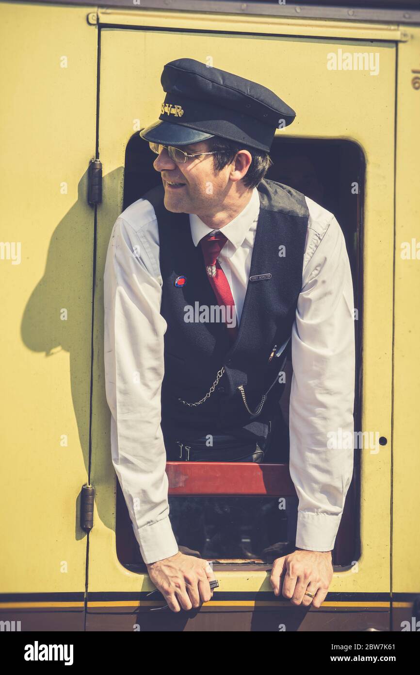 Close up of isolated ticket inspector leaning out of vintage railway ...