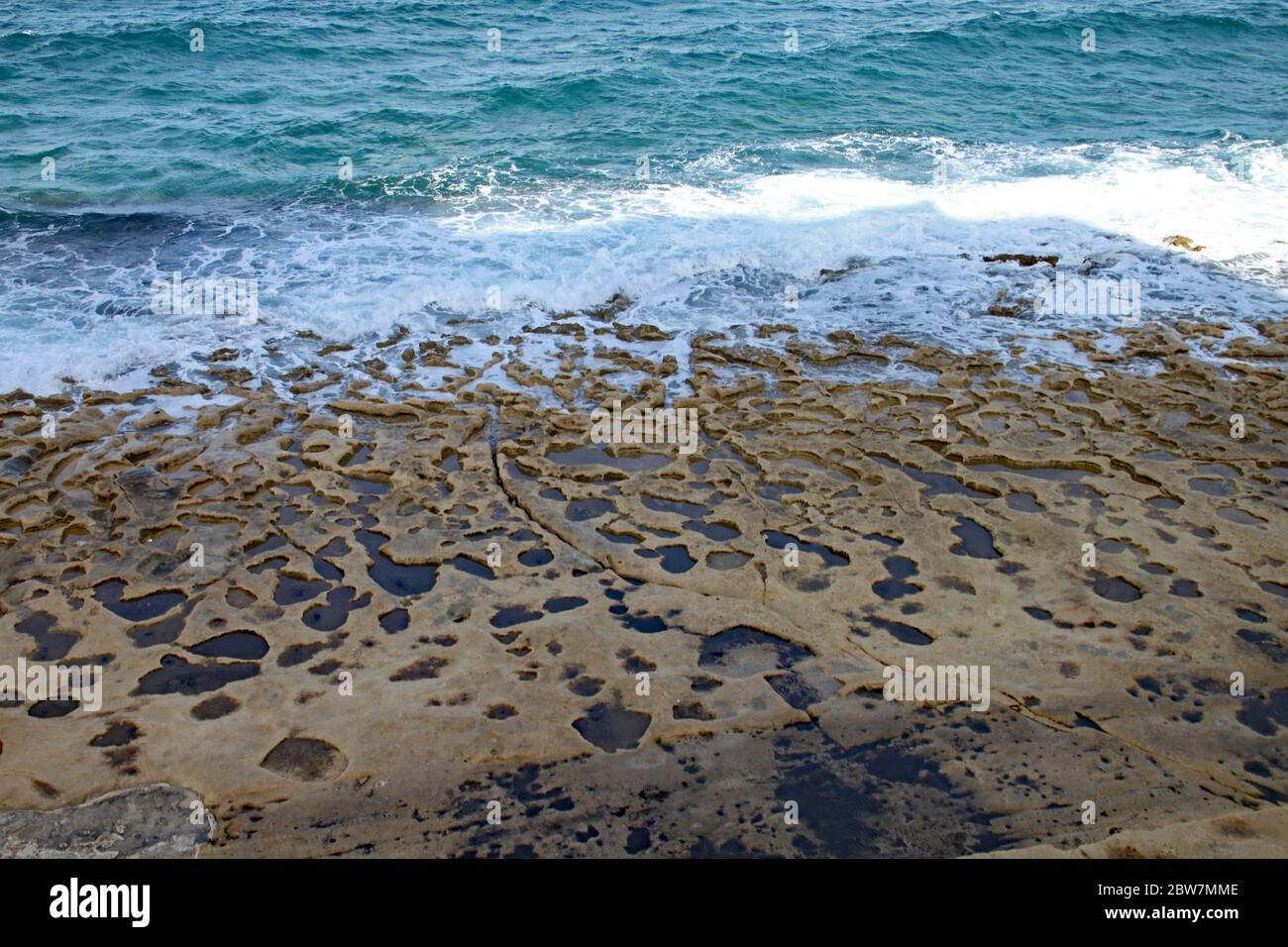 The rock pools in the sandstone shelf on the beach at Sliema, Malta ...