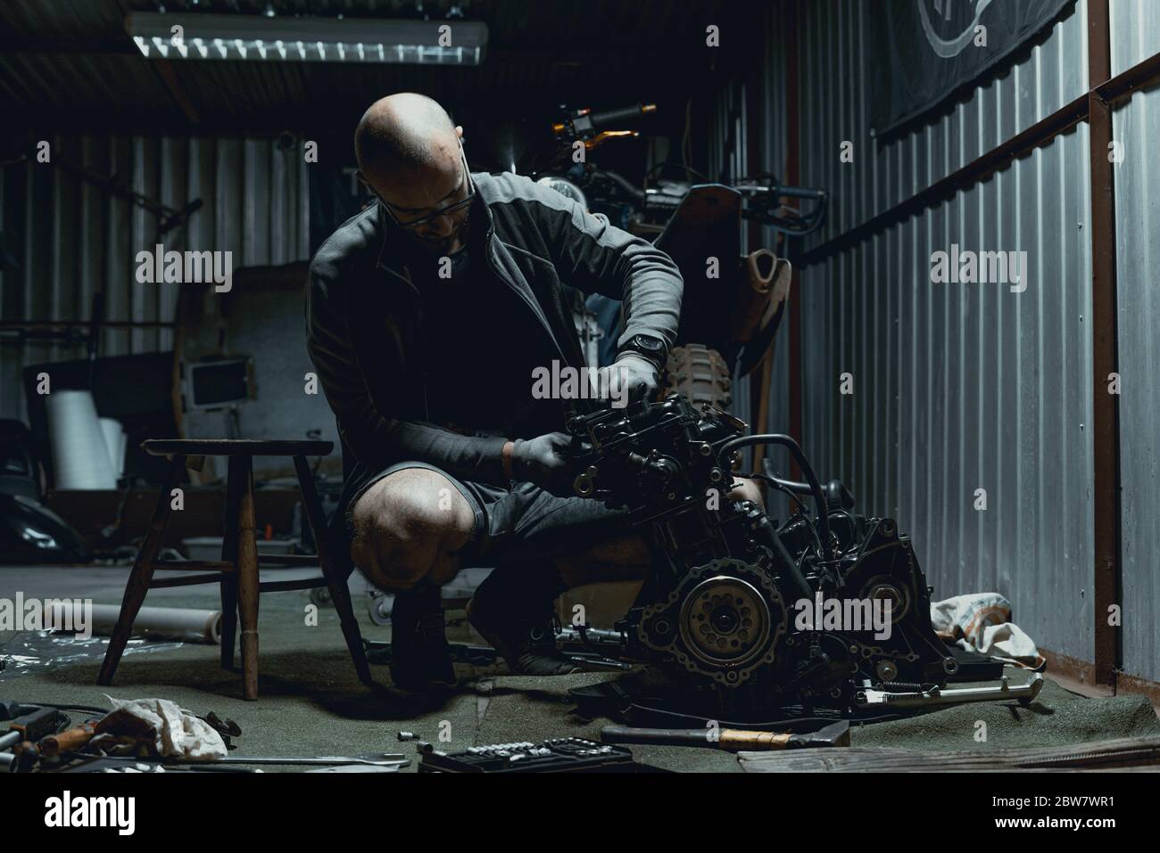 Young man repairing his motorcycle engine in the garage. The motorcycle ...