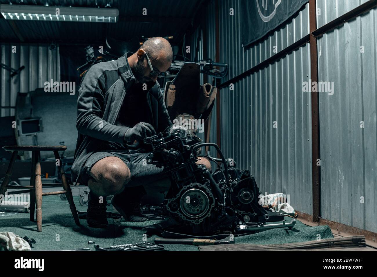 Young man repairing his motorcycle engine in the garage. The motorcycle ...