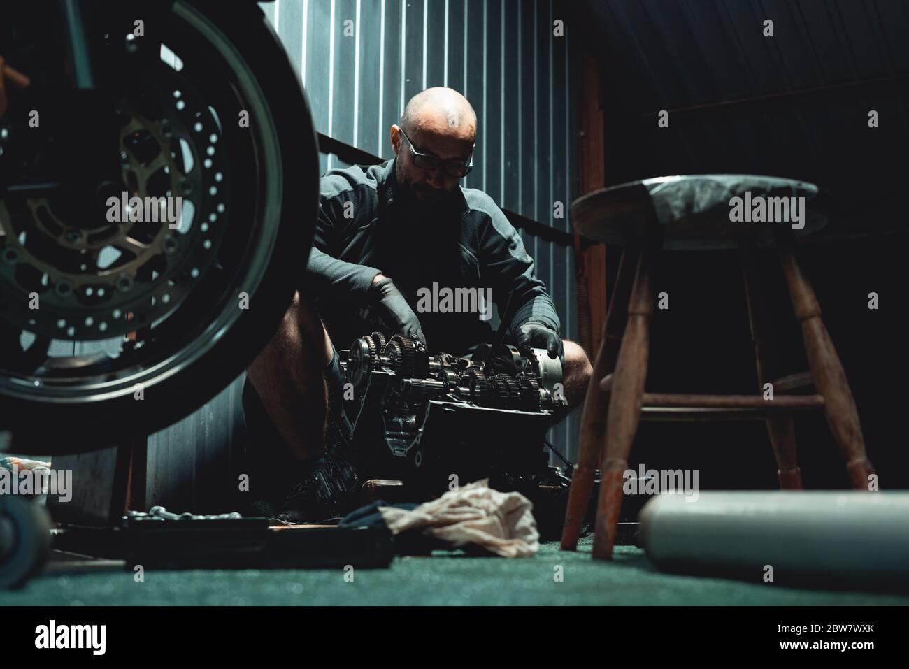 Young man repairing his motorcycle engine in the garage. The motorcycle ...