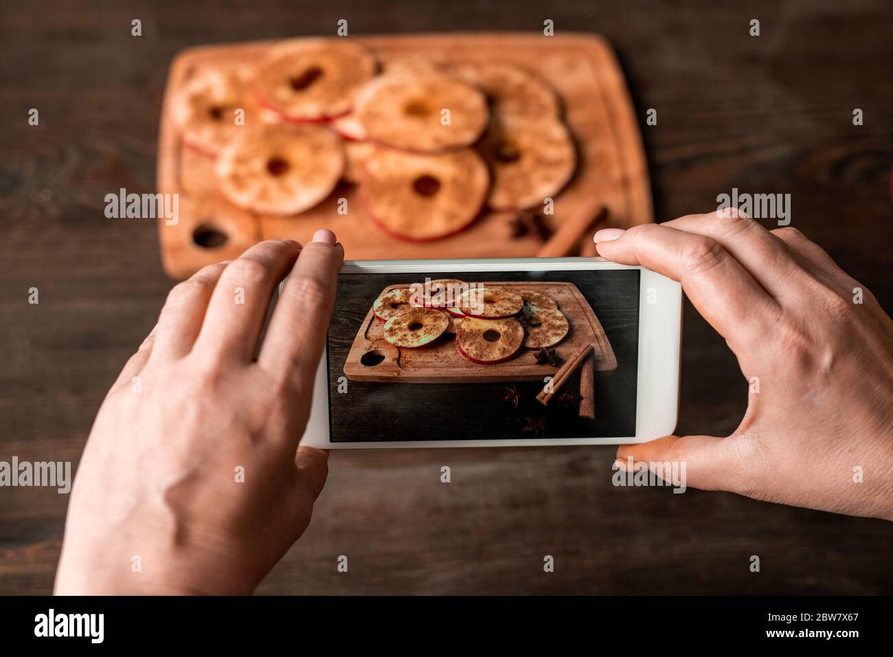 Hands of housewife with smartphone taking photo of slices of fresh ...