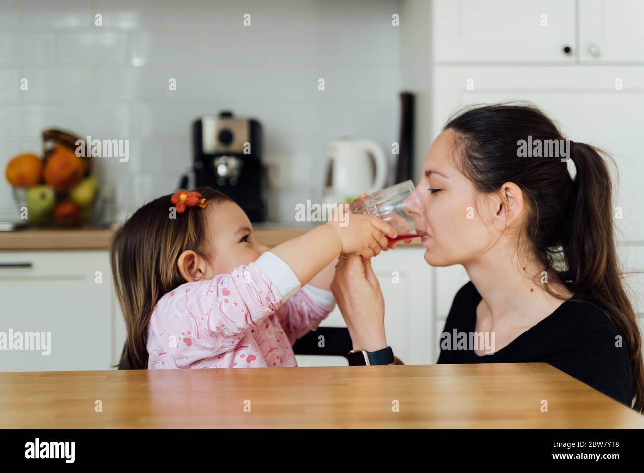 Young woman with baby in kitchen.Drinking a glass of juice. Child ...