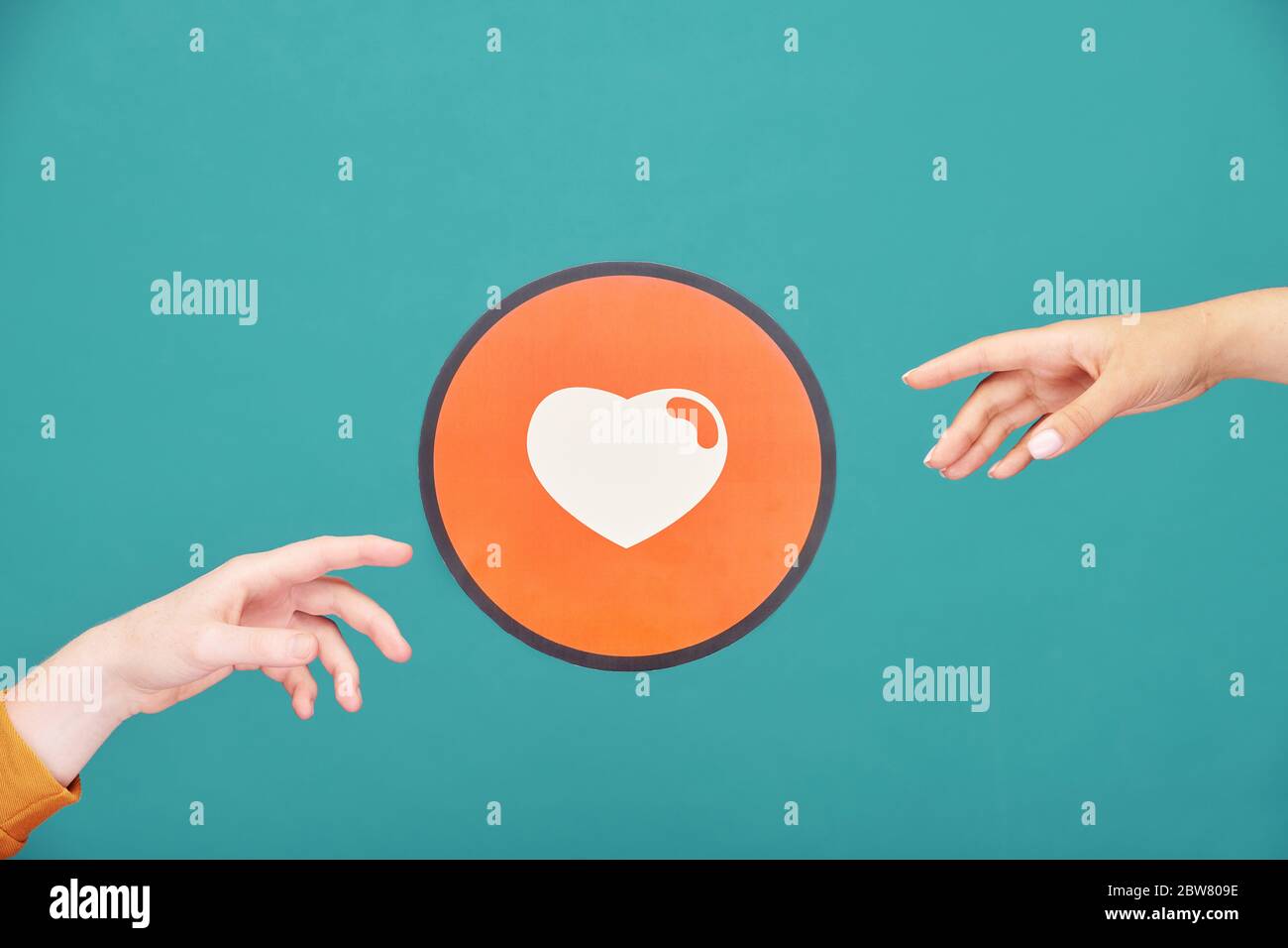 Hands of young man and woman reaching out for picture of white heart in ...
