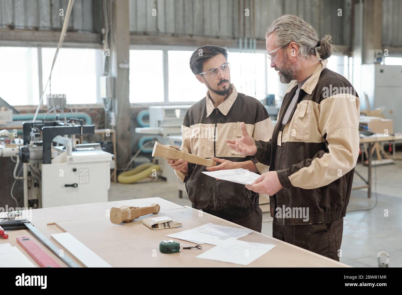 Aged professional engineer explaining his young trainee sketch of ...
