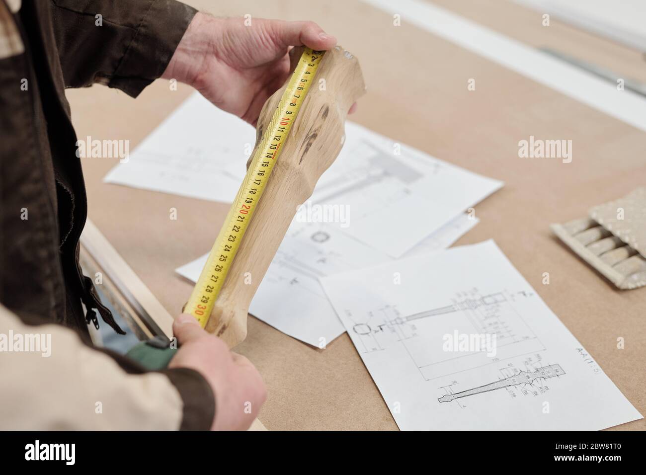 Modern factory worker measuring wooden part of furniture while holding ...