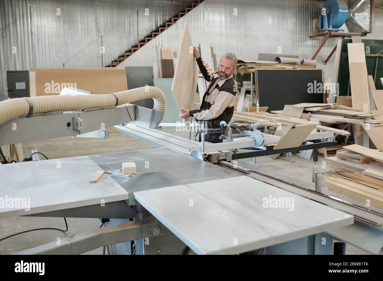 Senior worker of furniture producing factory in uniform putting large ...
