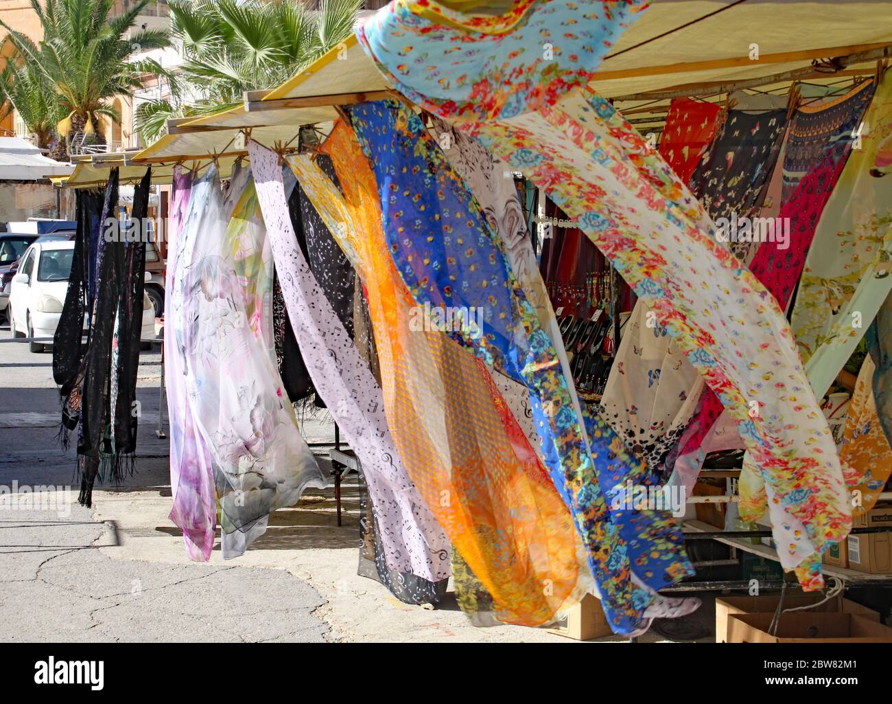 Multi coloured patterned silk scarves blowing in the breeze on a market ...