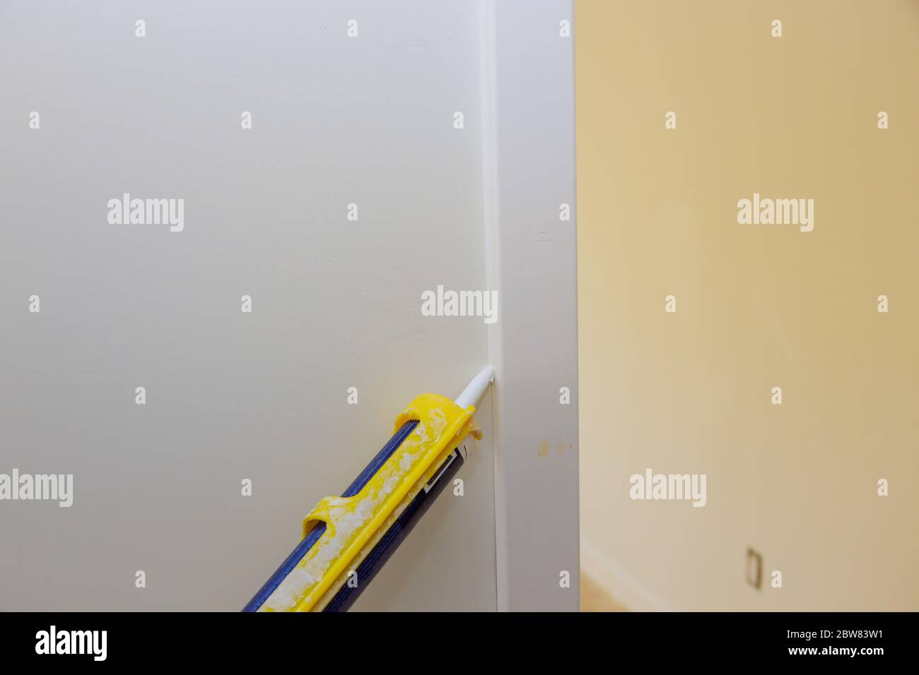 Worker hands applying filling silicone for sealing on corner wall door ...