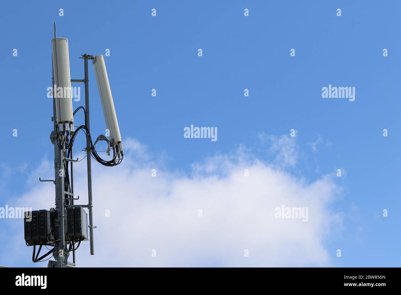 Cellular, mobile phone transmitter tower with blue sky and clouds middle Stock Photo - Alamy