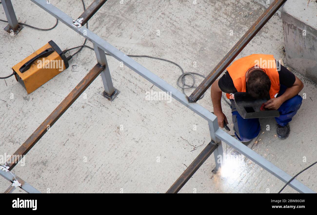 One construction worker welding a metal profile square structure ...