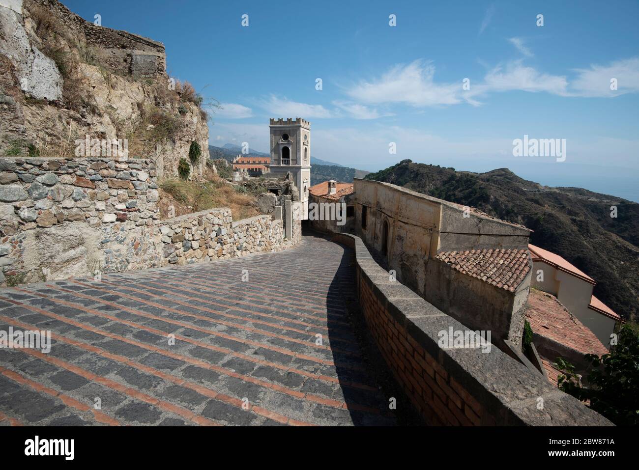Looking down a narrow paved street to a church in the town of Savoca ...
