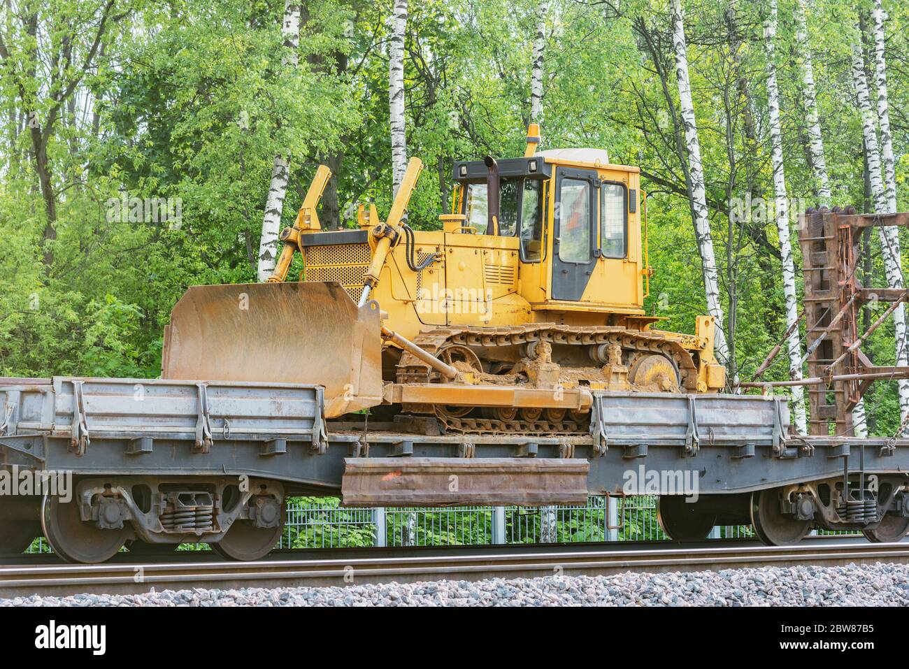Bulldozer stands on the railway transporter by the forest Stock Photo ...