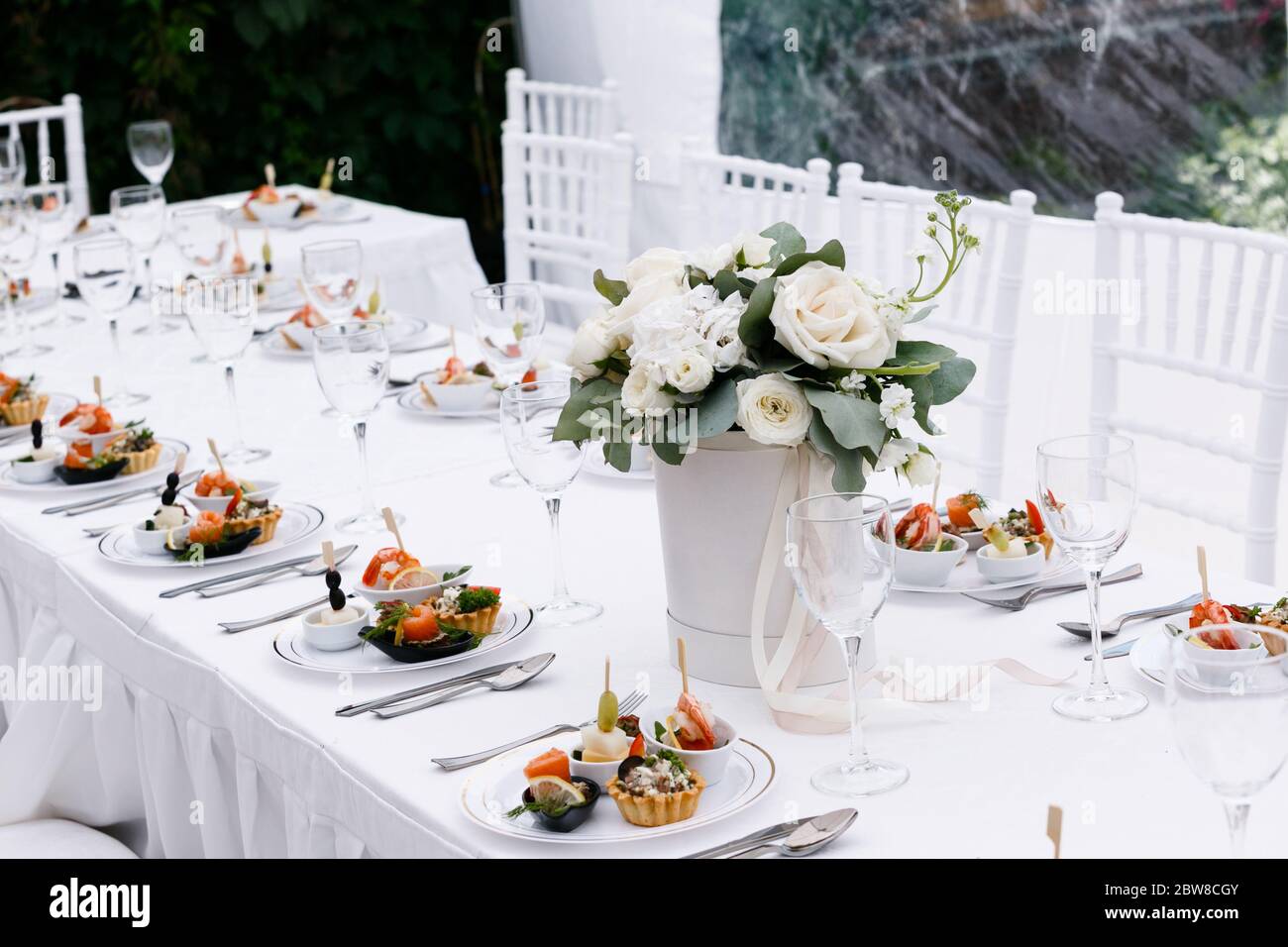 Elegant table setting. White tablecloth, appetizers, vase with delicate ...