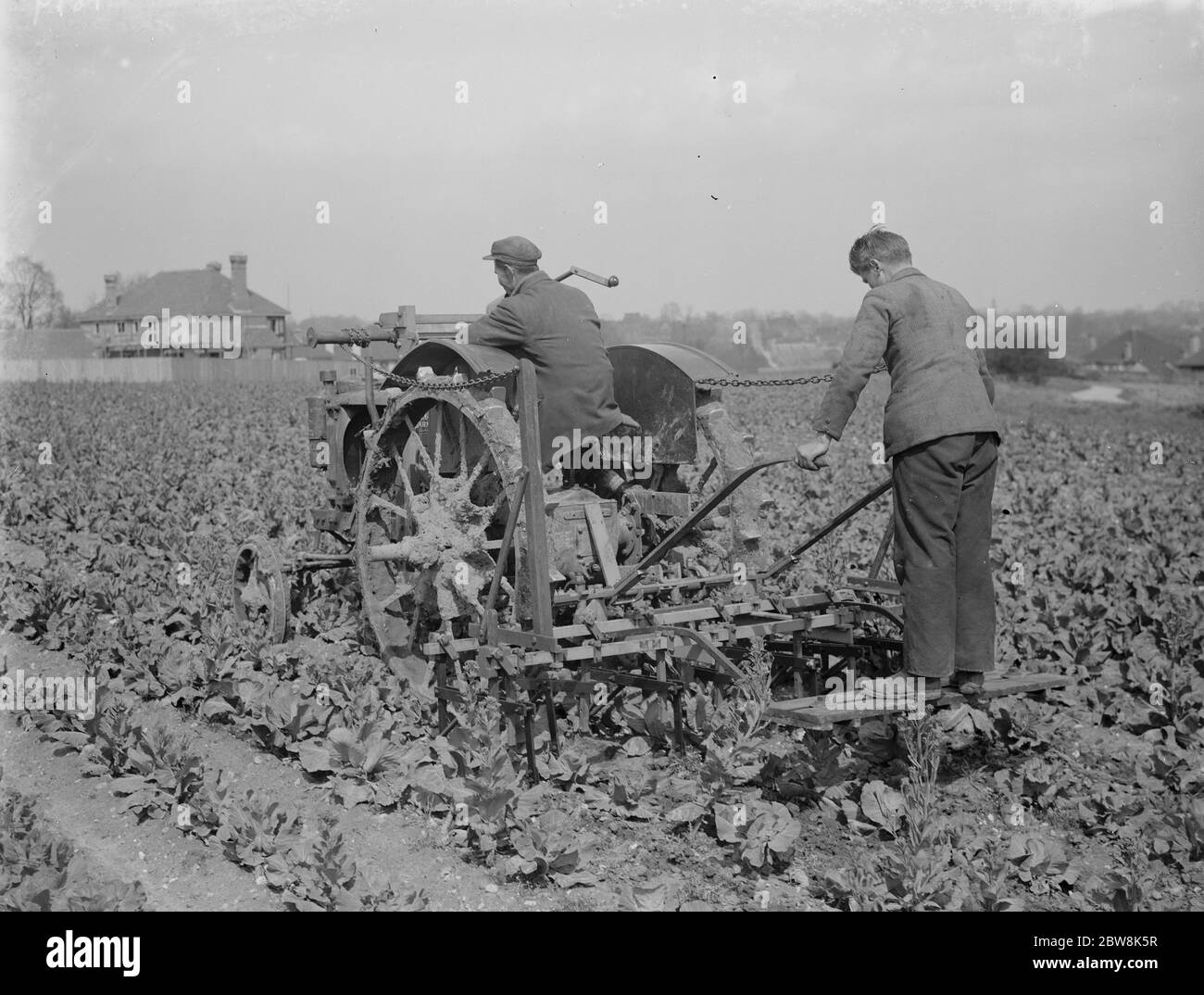 Farm workers on a tractor cultivate a field . 1935 Stock Photo - Alamy