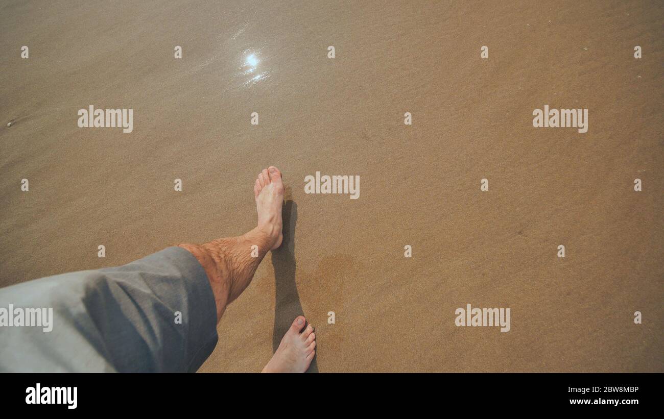 A man walks along the beach arambol. Kind of just legs Stock Photo - Alamy