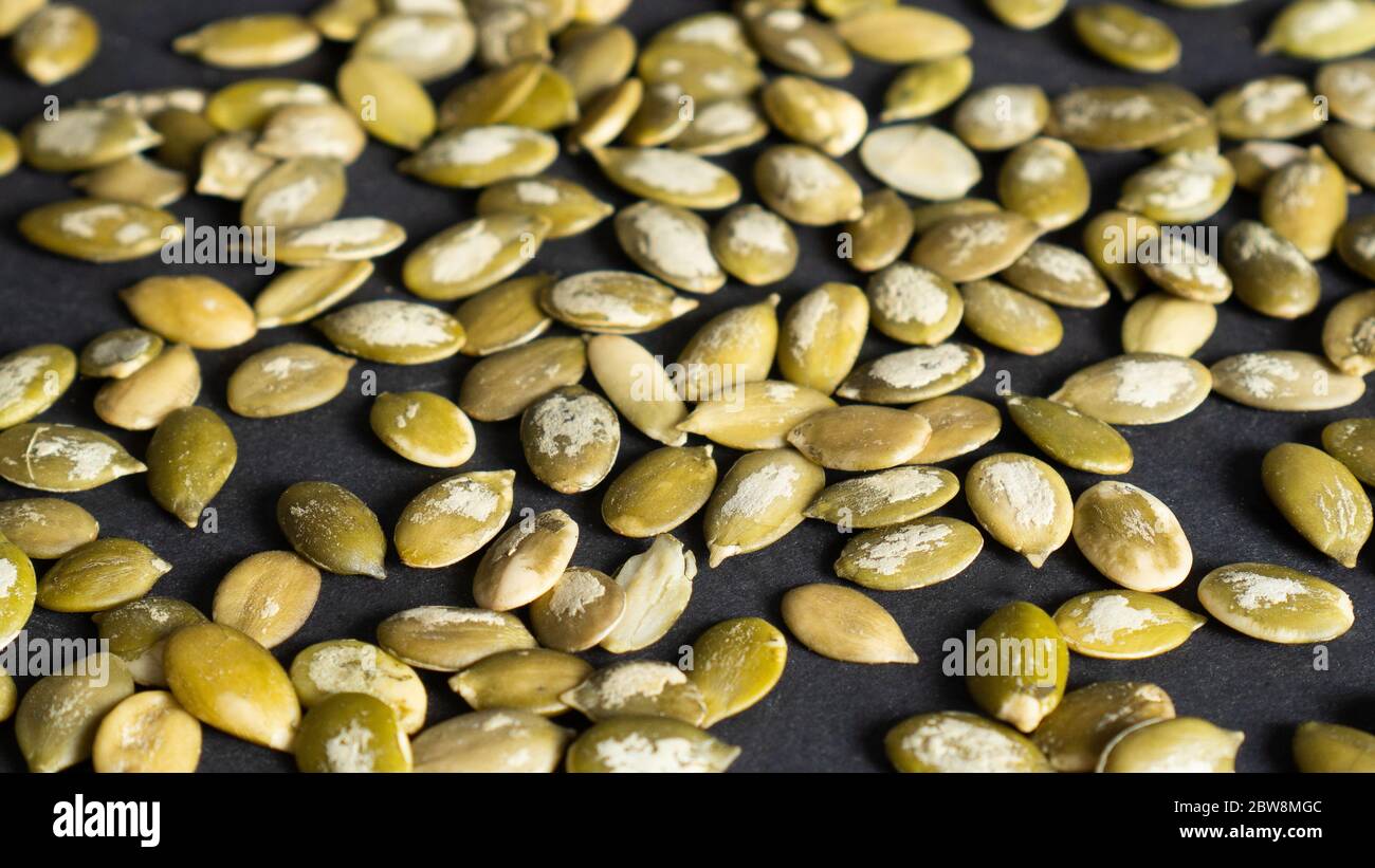 Scattered peeled pumpkin seeds as background. Top view of macro ...