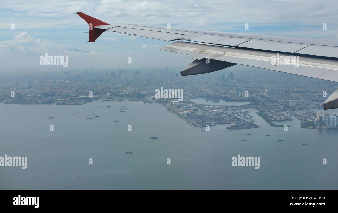 The plane flies against the background of the city of Jakarta ...