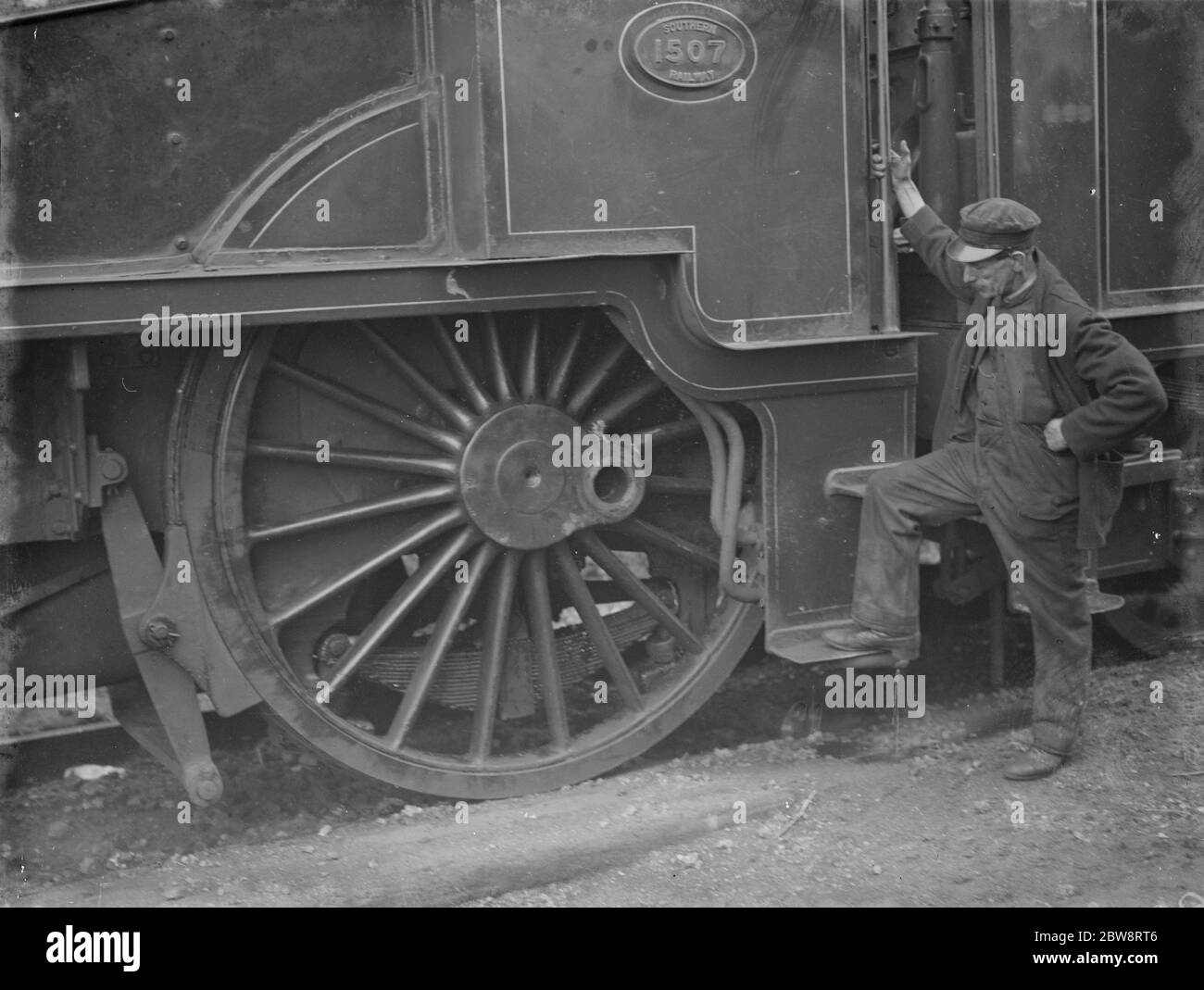 A train engineer looks at one of the large engine wheels after being ...