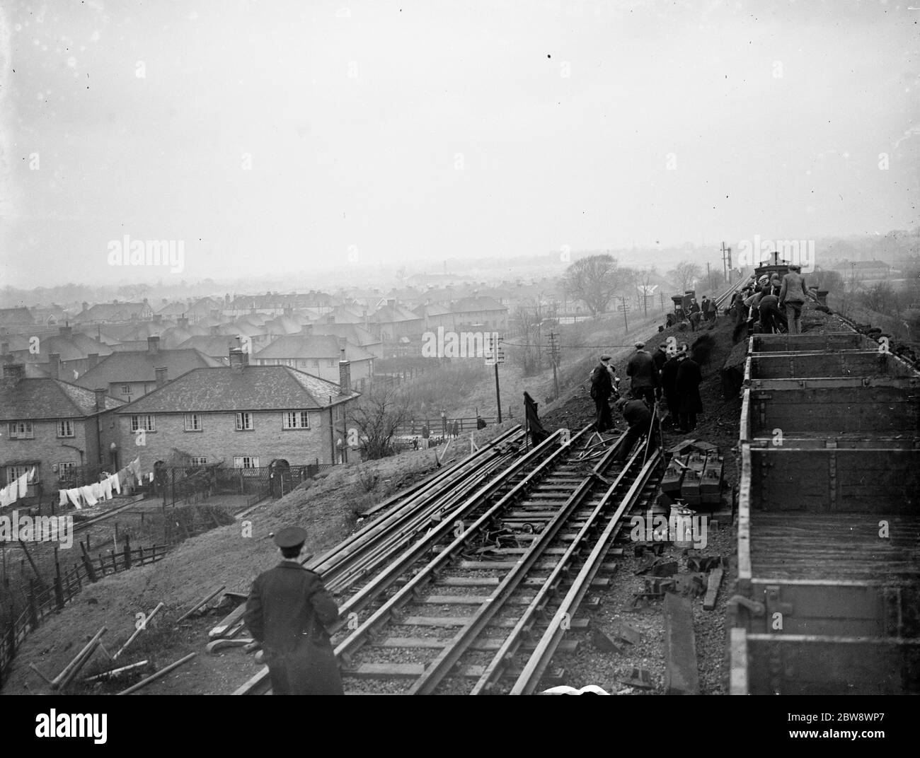 Rail workers work to clear the land slide and re lay track on the ...