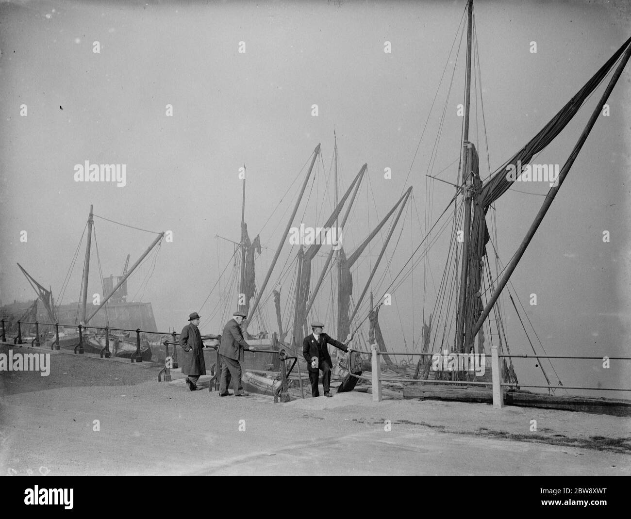 Old men on the riverside by the moored Thames sailing barges at ...