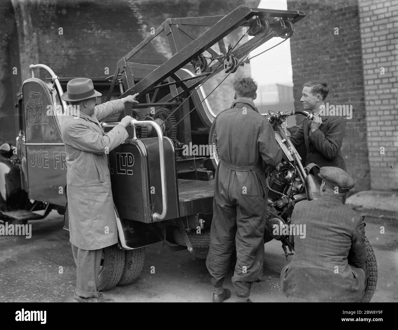 A speedway motorbike is loaded onto the back of a Bedford winch truck ...