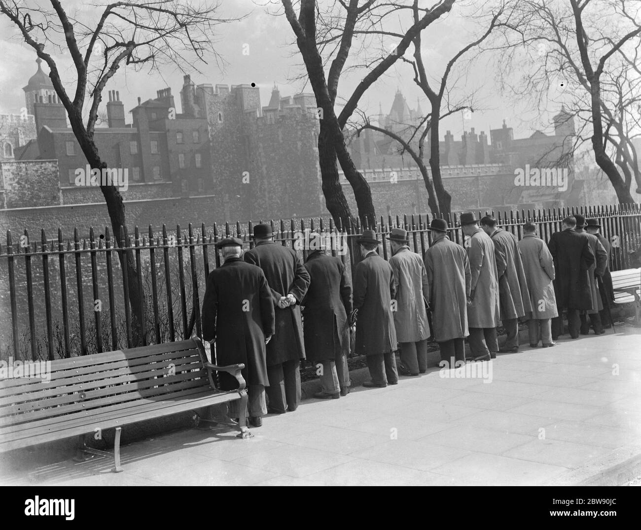 Men looking through railings to the marching soldiers outside the Tower ...