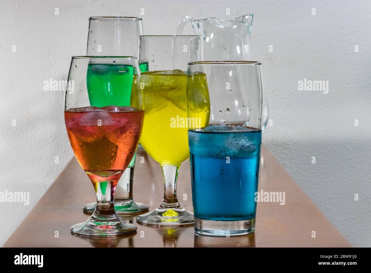 multi colored liquid in pretty glasses with iceon table Stock Photo - Alamy