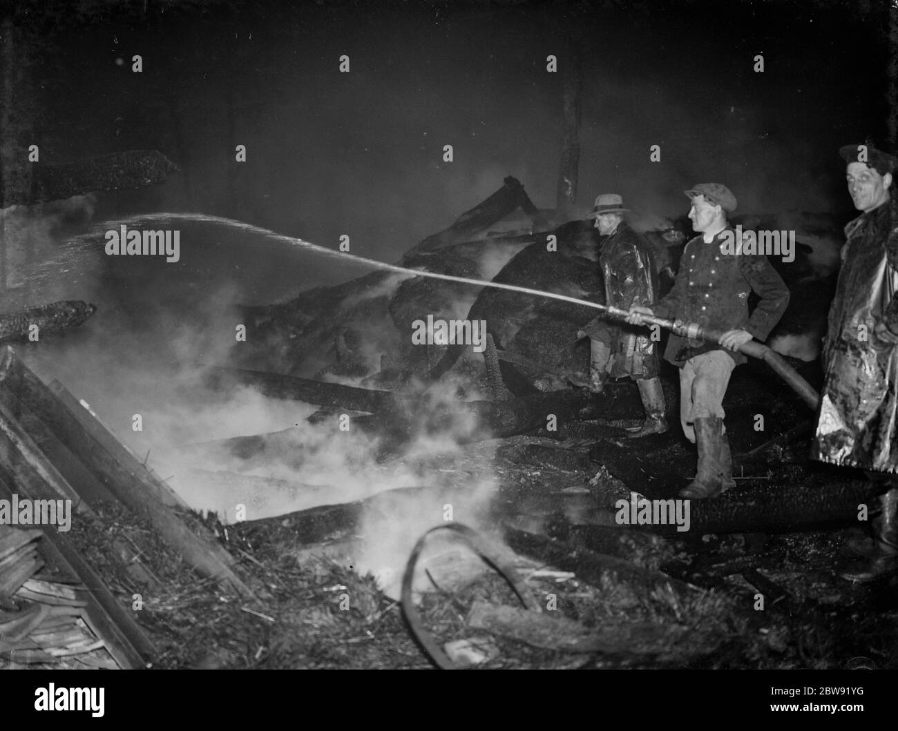 Fire at Chaplin ' s Farm , Hockenden , Kent . Hosing down the embers ...
