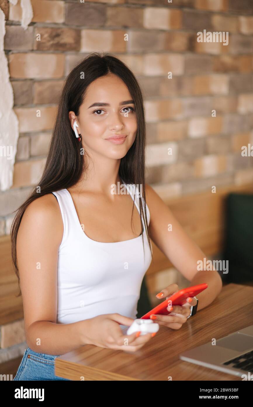 Attractive young girl use wireless headphones and working on laptop ...