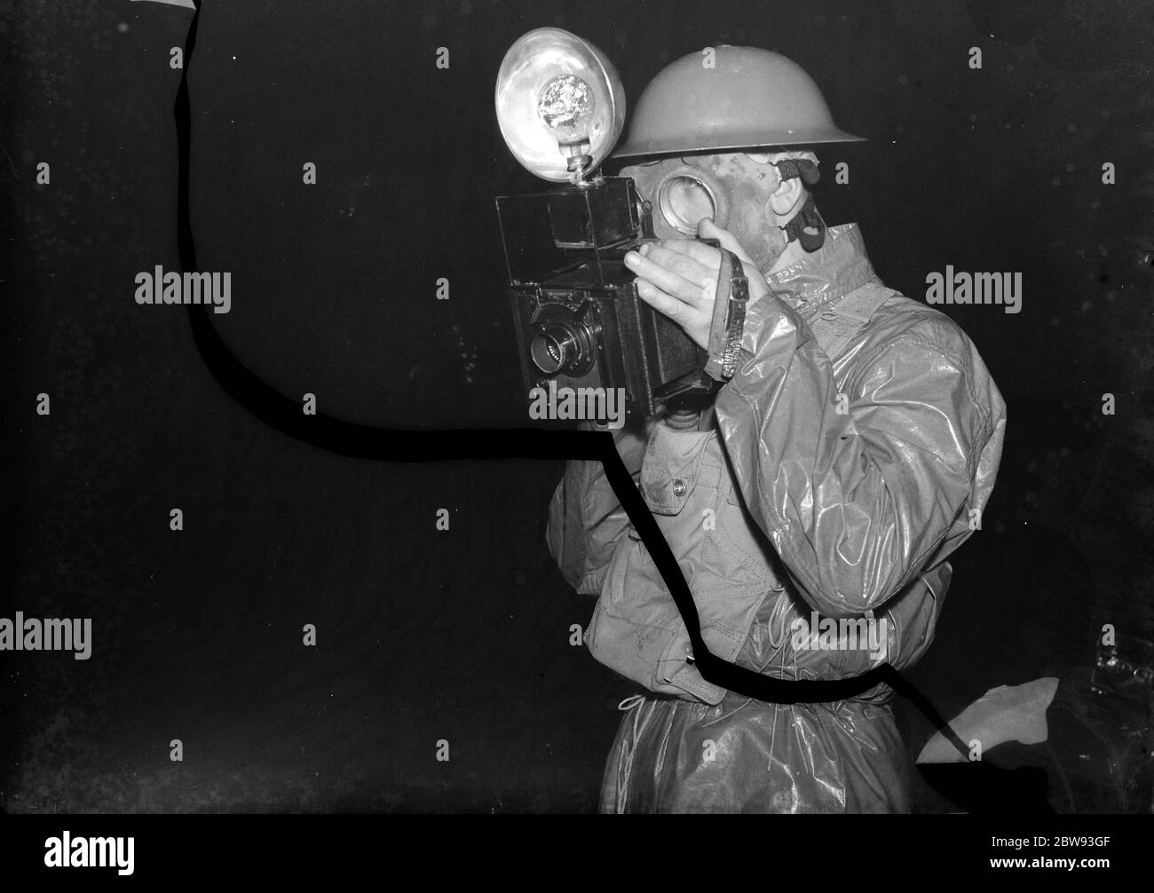 A press photographer in a ARP ( Air Raid Precautions ) gas suit ...