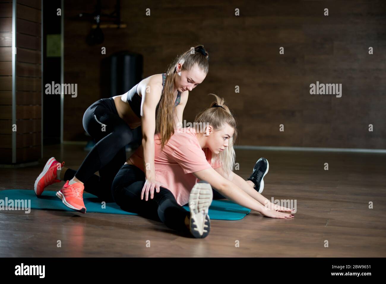 girl helps stretching her friend after a workout. Paired trainings with ...