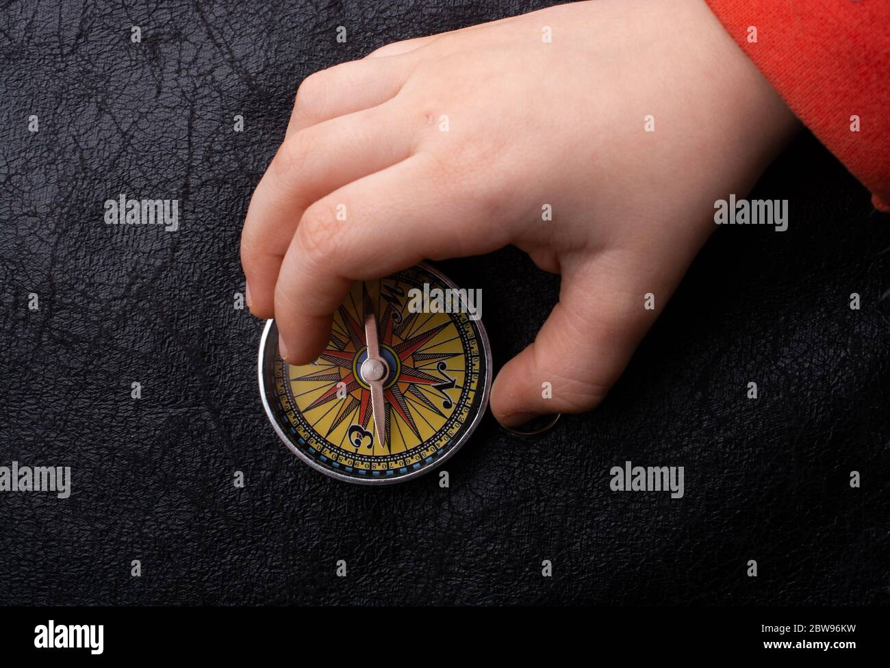 Hand is holding a magnetic compass on black background Stock Photo - Alamy