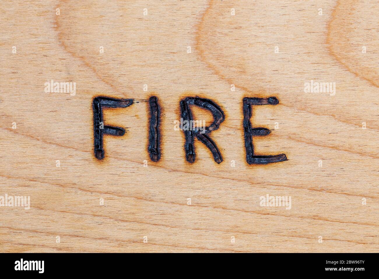 the word fire handwritten on wooden surface with electrical woodburner ...