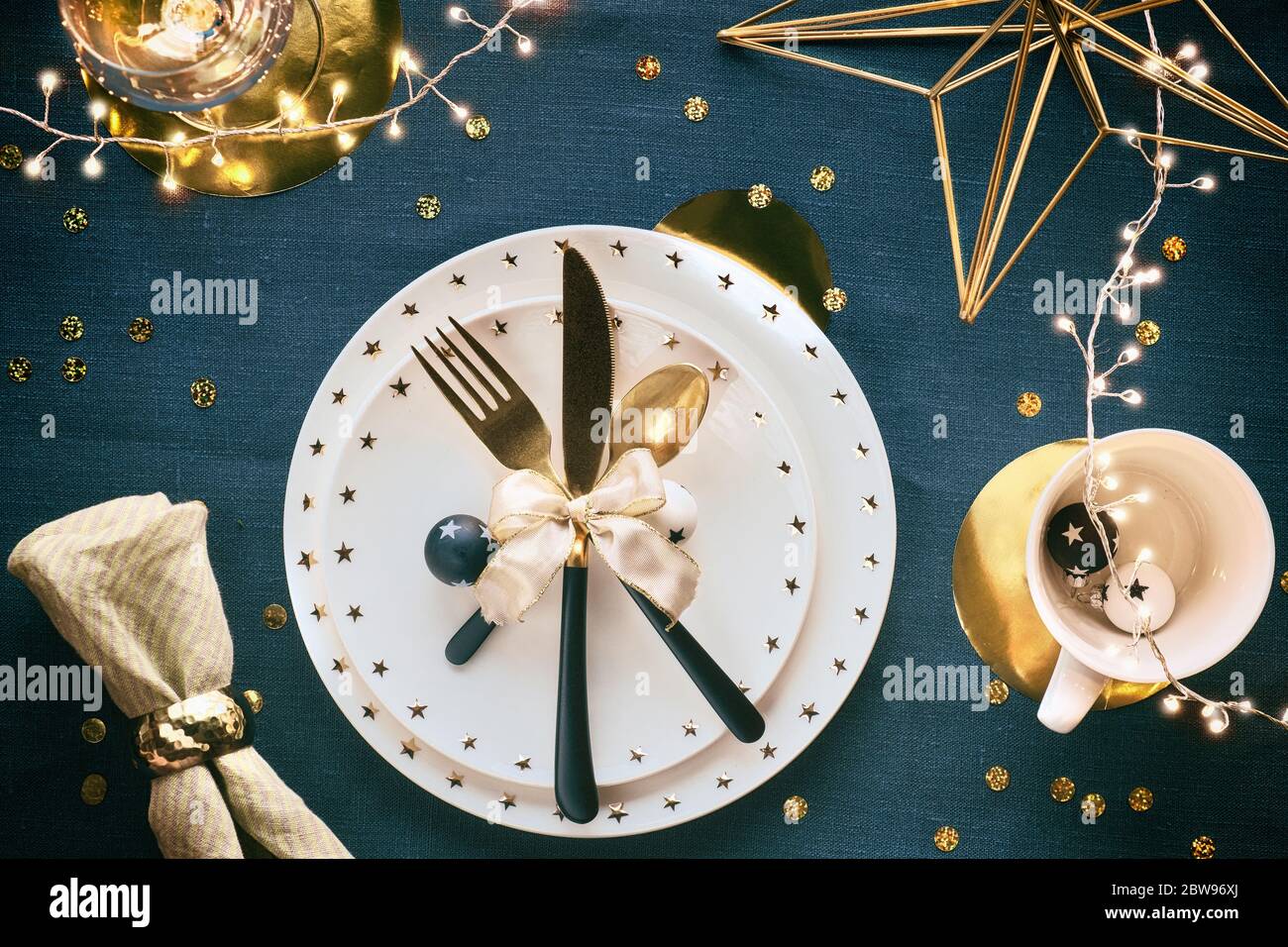 Christmas table setup with white plate, golden utensils and gilded ...