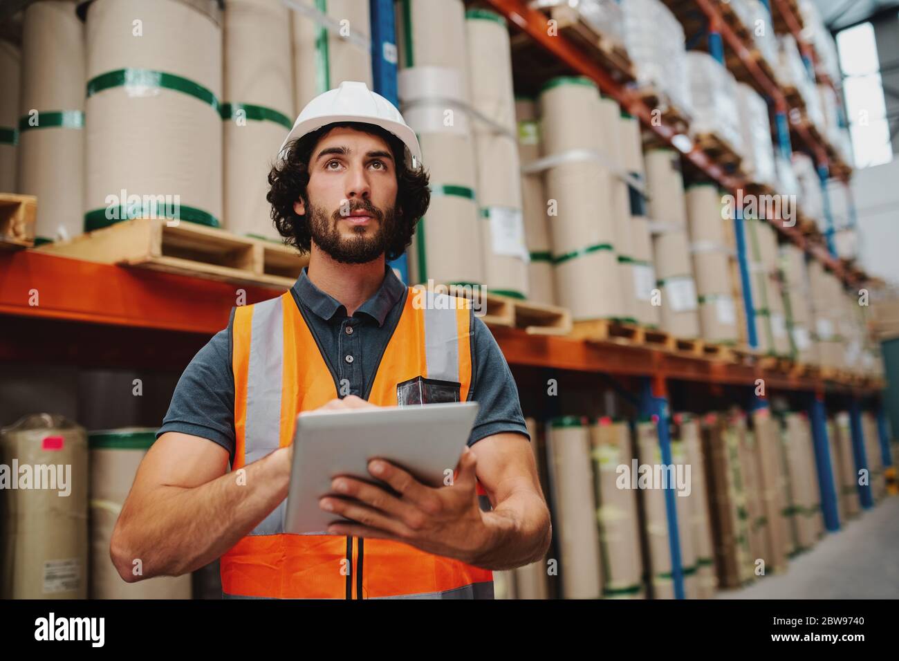 Young caucasian male worker doing stocktaking of product in cardboard ...
